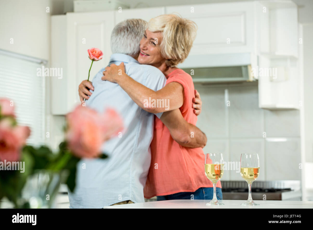 Smiling senior woman hugging man with rose Stock Photo - Alamy