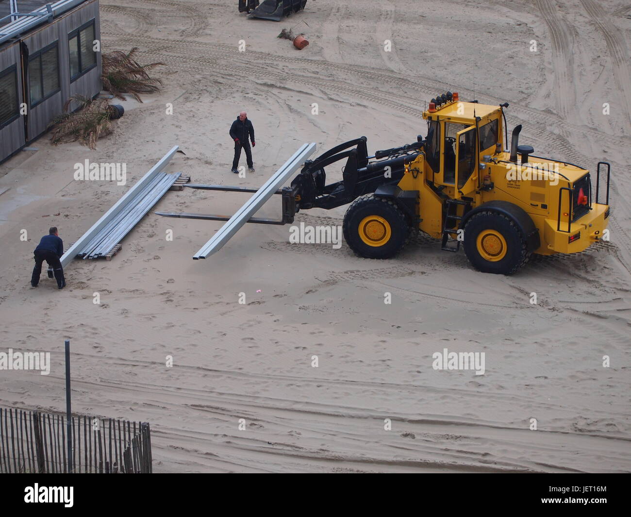 Earth mover moving steel bars on a sandy beach Stock Photo - Alamy