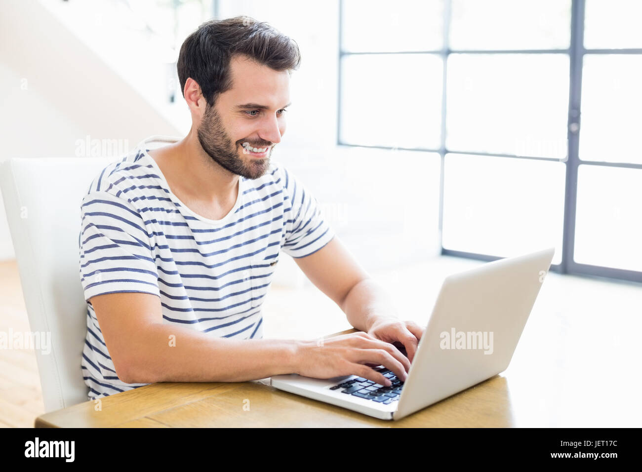 Happy man sitting on table and using laptop Stock Photo - Alamy