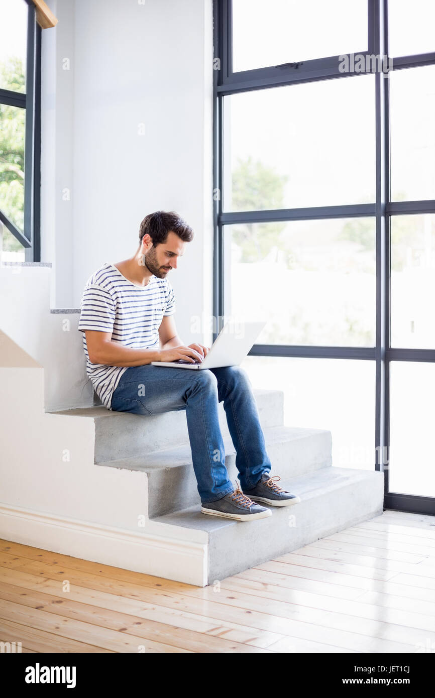 Happy man sitting on steps using laptop Stock Photo - Alamy