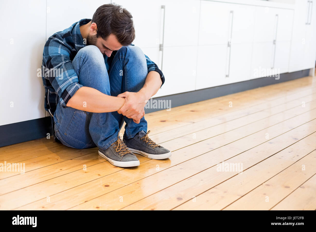 Tensed man sitting on wooden floor Stock Photo - Alamy
