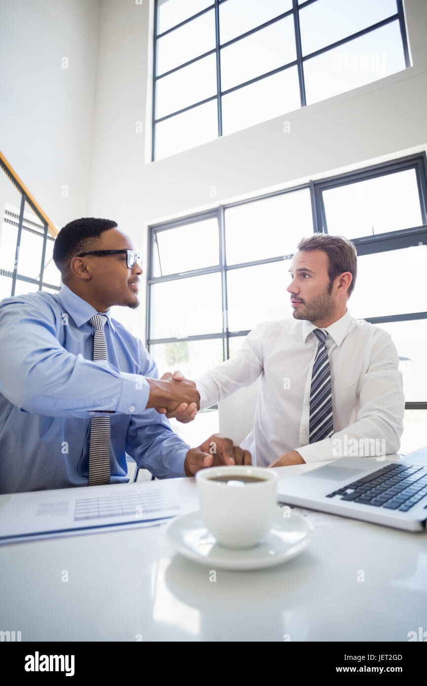 Businessmen shaking hands in office Stock Photo - Alamy