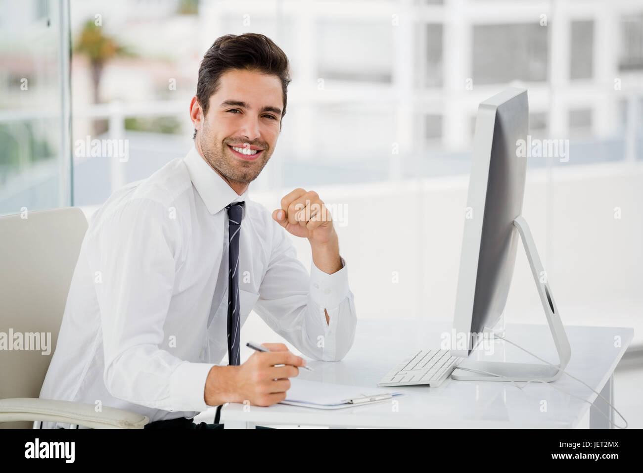 Businessman using computer and taking notes Stock Photo - Alamy