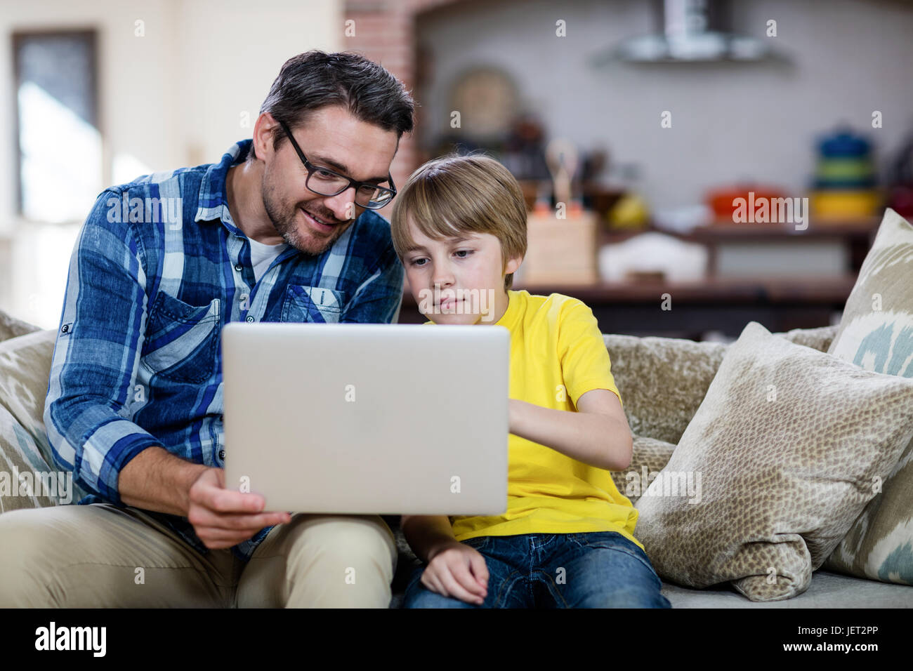 Father and son using laptop in living room Stock Photo - Alamy