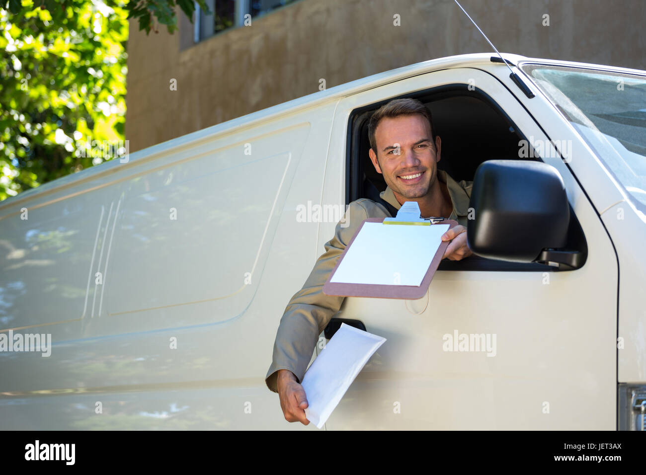 Smiling delivery man sitting in his van Stock Photo - Alamy