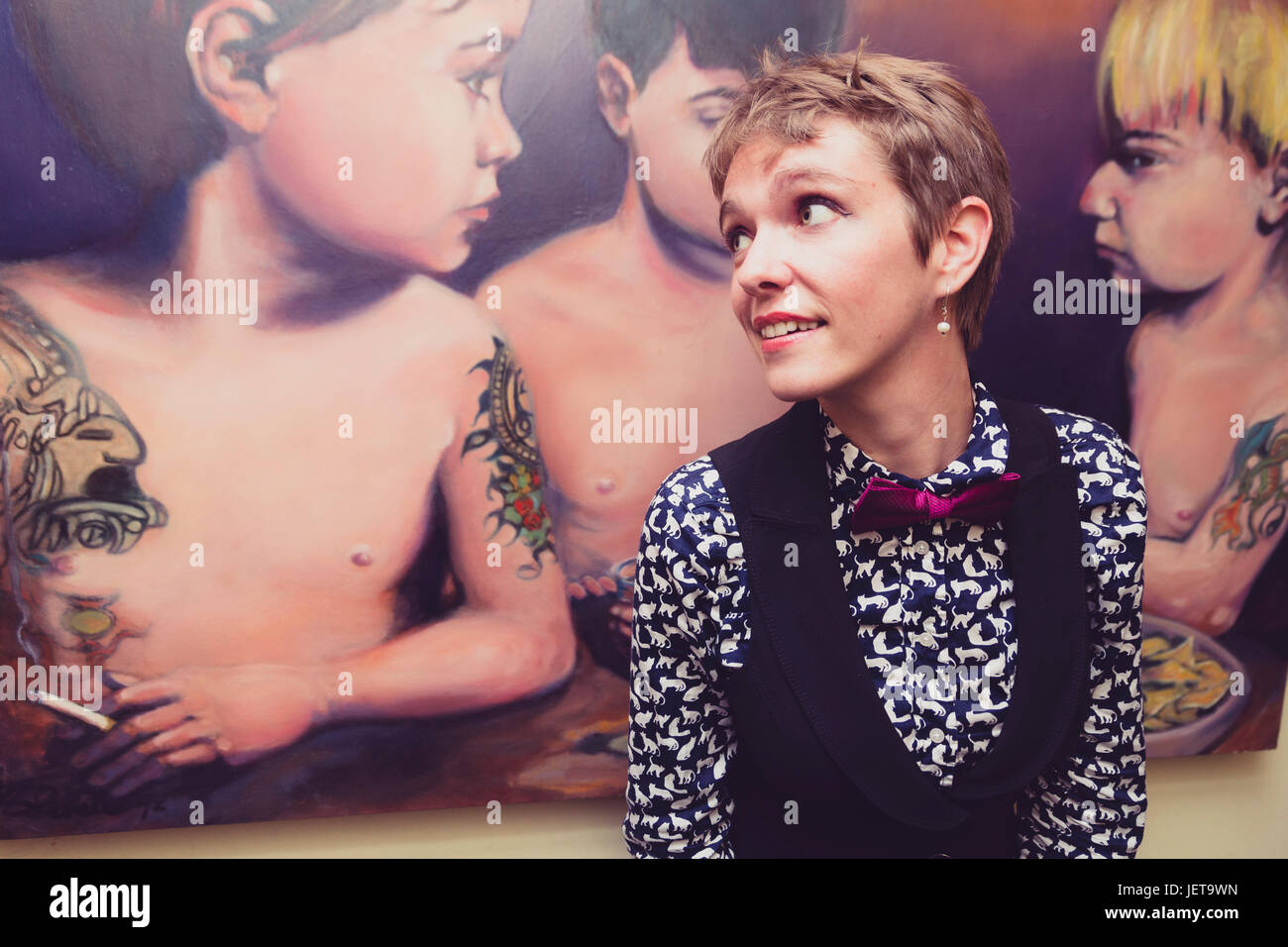 A young caucasian woman with androgynous features wears formal clothing ...