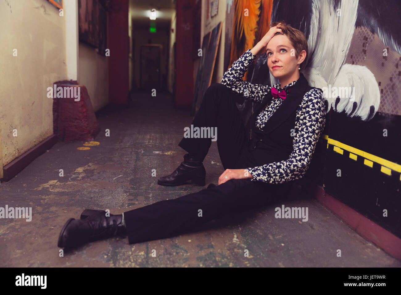 A young caucasian woman with androgynous features wears formal clothing ...