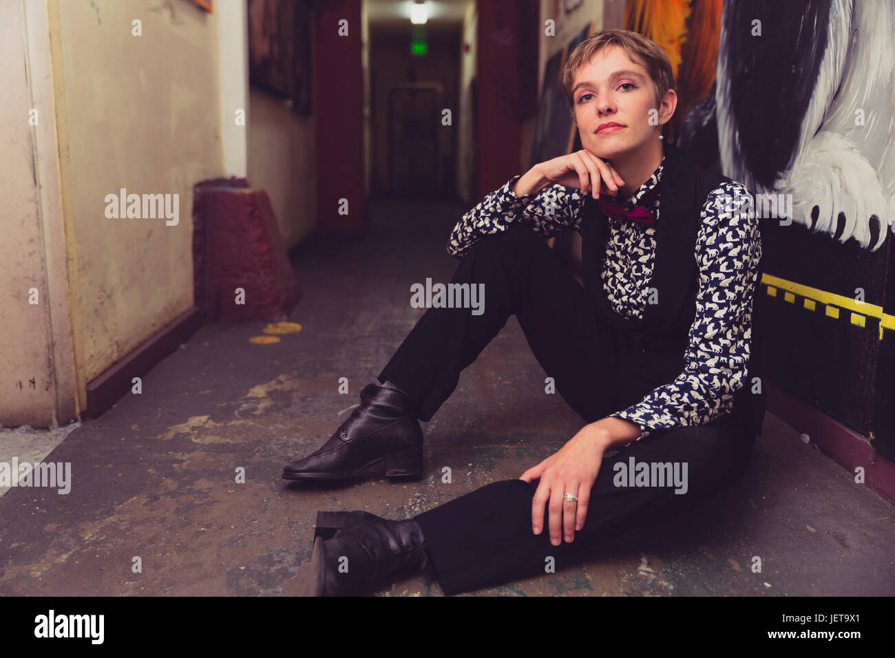 A young caucasian woman with androgynous features wears formal clothing ...