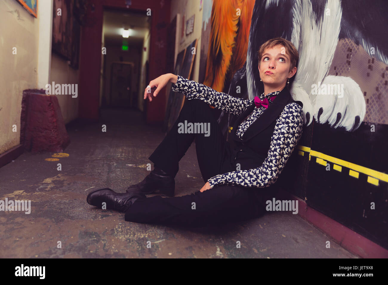 A young caucasian woman with androgynous features wears formal clothing ...