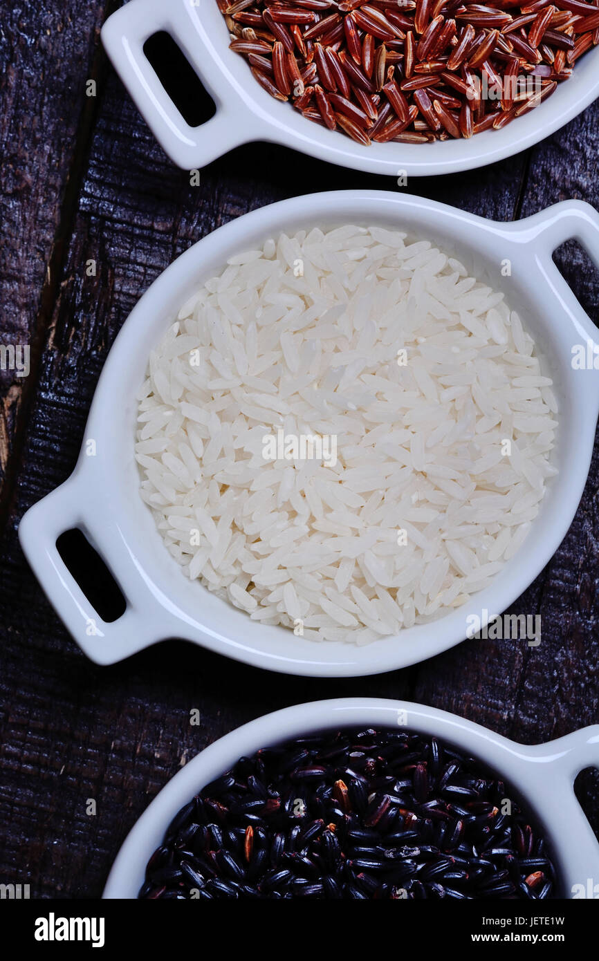 Bowls with different types of rice on wooden table Stock Photo - Alamy