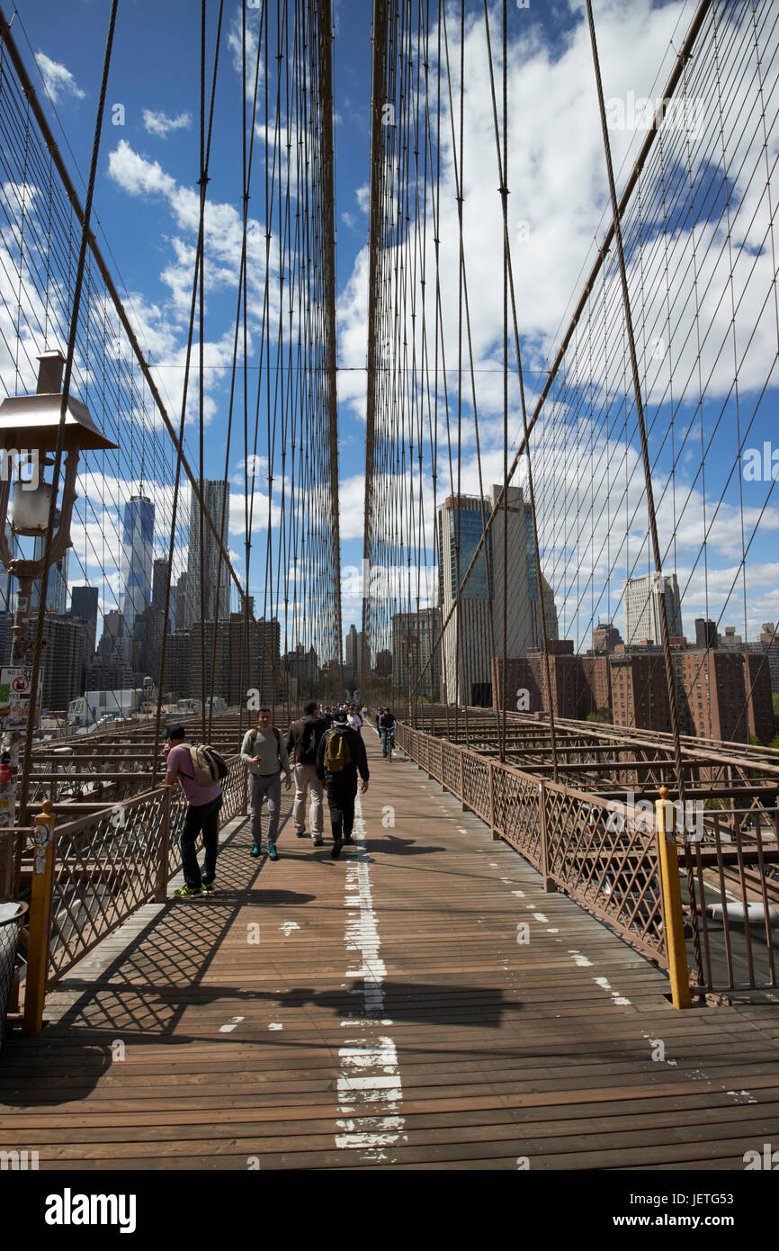 people walking over the brooklyn bridge between cables towards lower ...