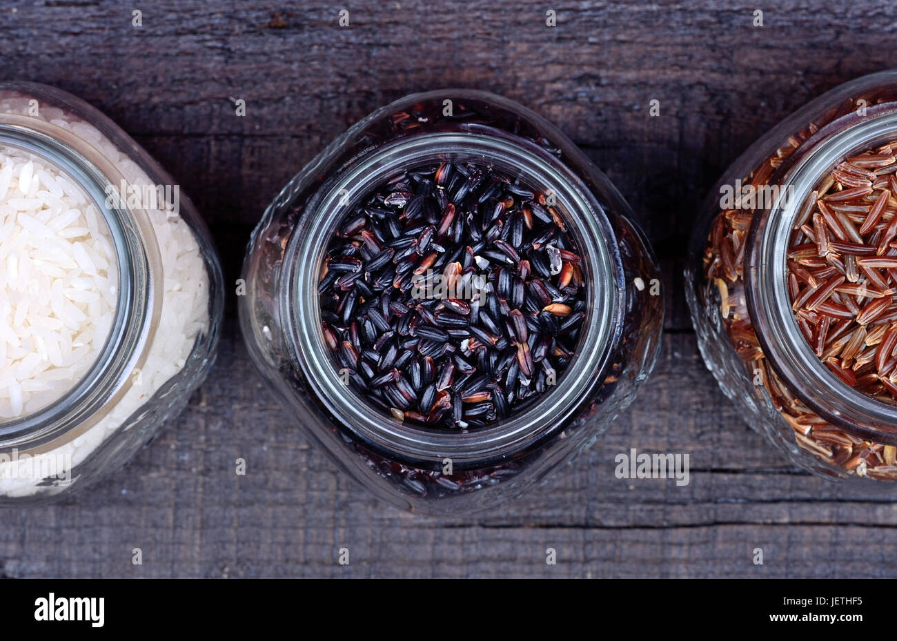 Various types of rice in a jars on wooden table Stock Photo - Alamy