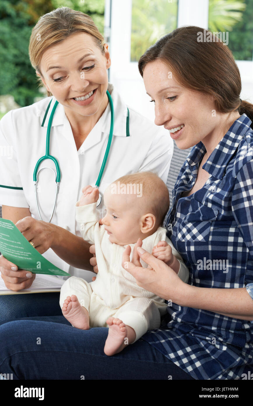Health Visitor Discussing Leaflet With Mother Holding Baby At Home ...