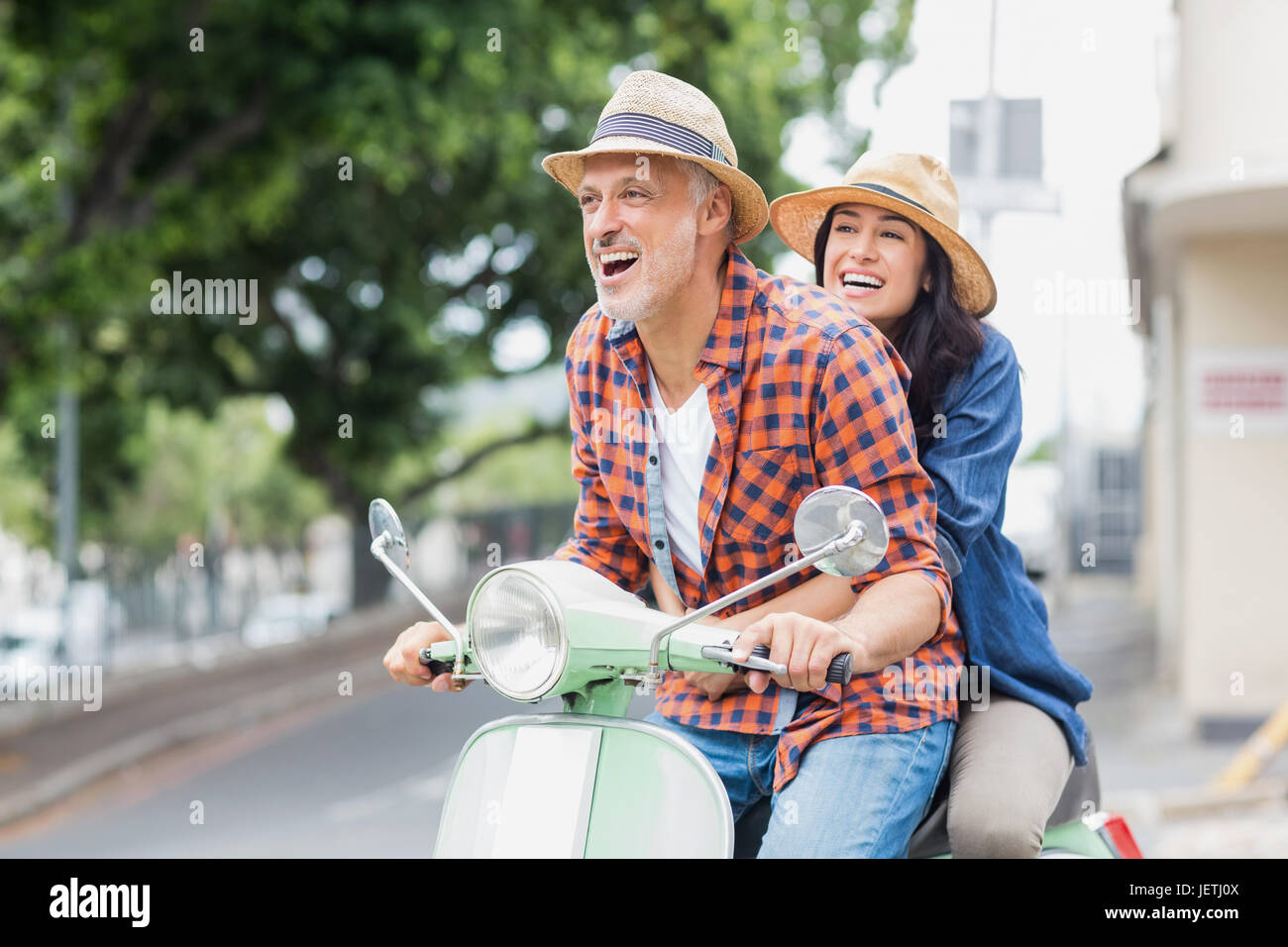 Excited couple riding moped Stock Photo - Alamy