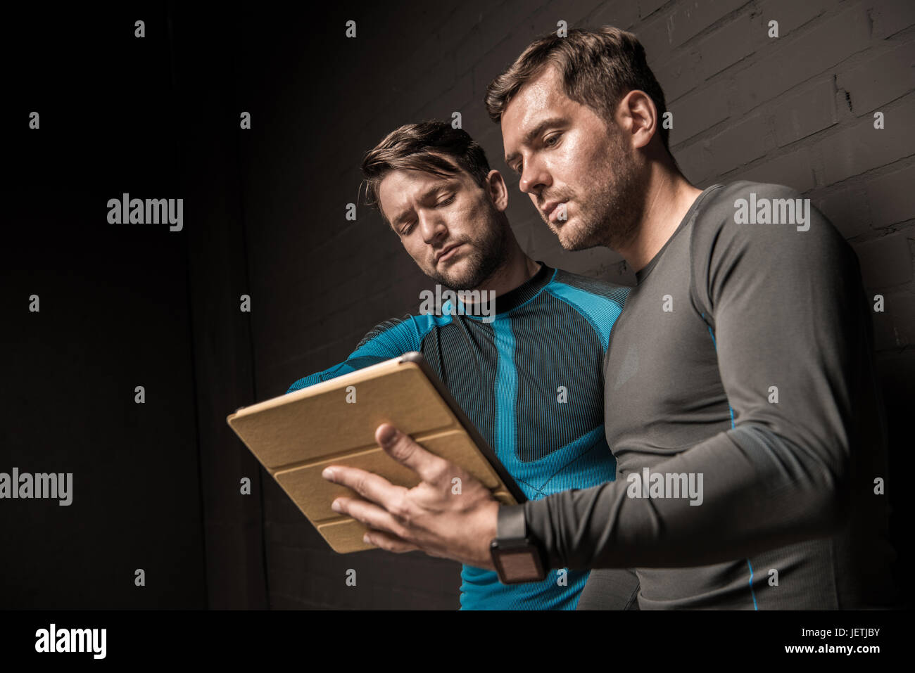 Handsome young men using tablet computer together Stock Photo - Alamy