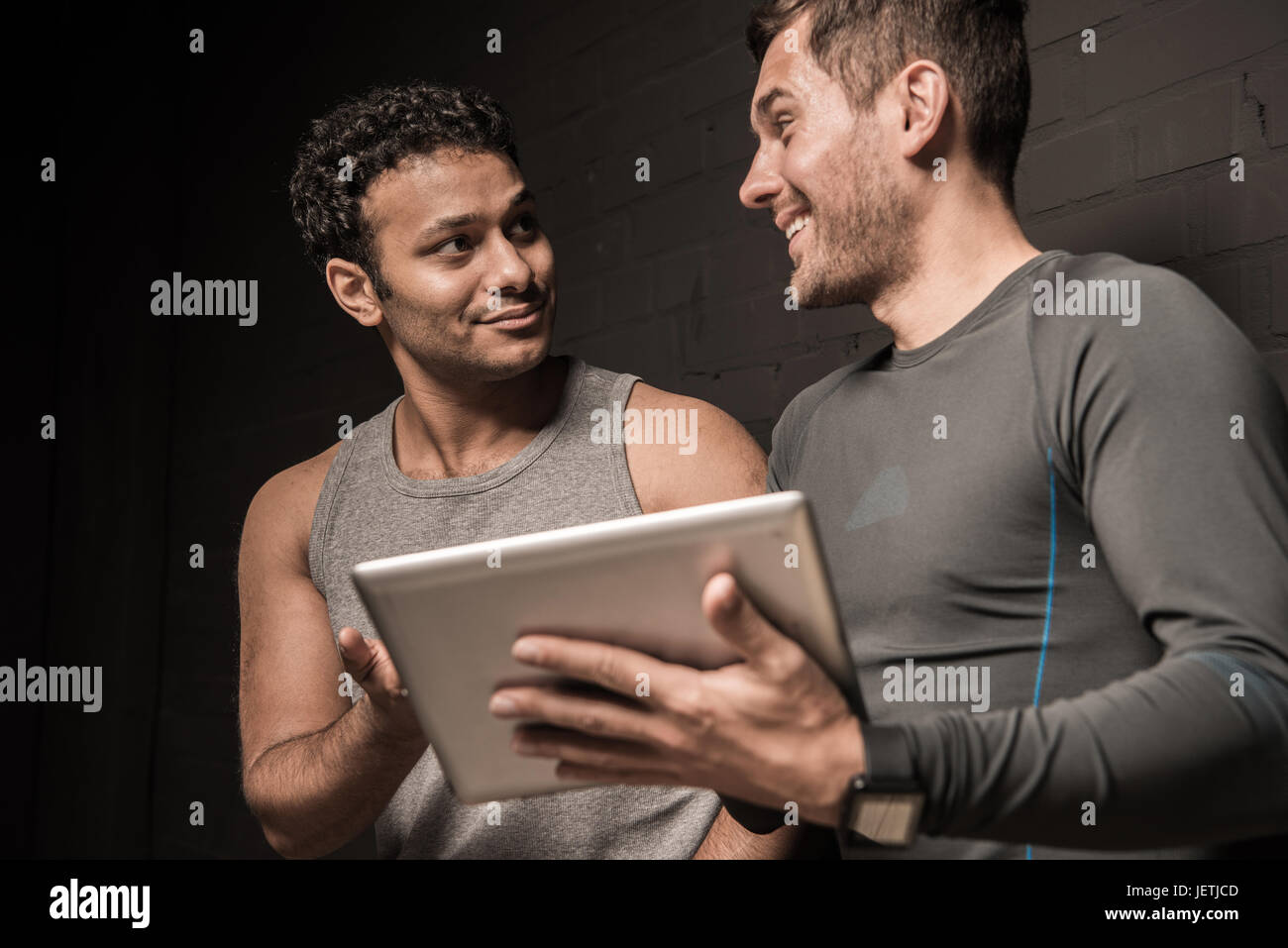 Handsome young men using tablet computer together Stock Photo - Alamy