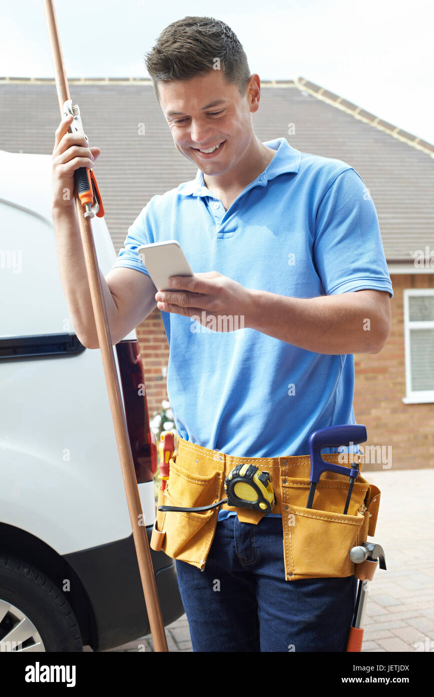 Plumber With Van Texting On Mobile Phone Outside House Stock Photo - Alamy