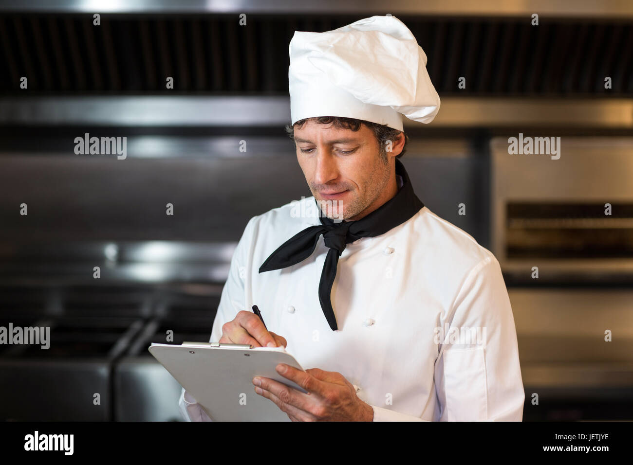 Chef writing on clipboard in kitchen Stock Photo - Alamy
