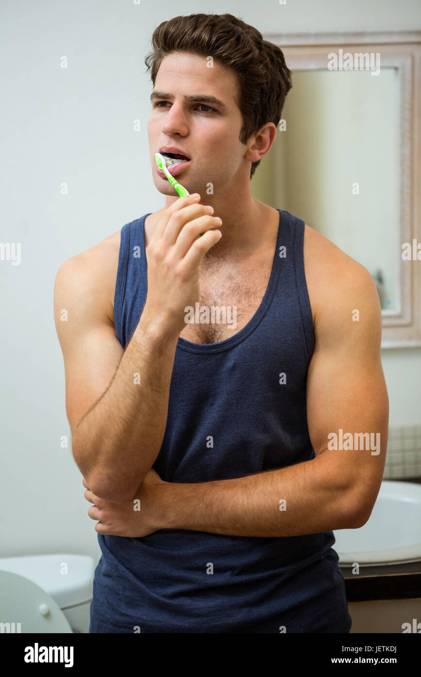 Young man brushing his teeth in bathroom Stock Photo - Alamy