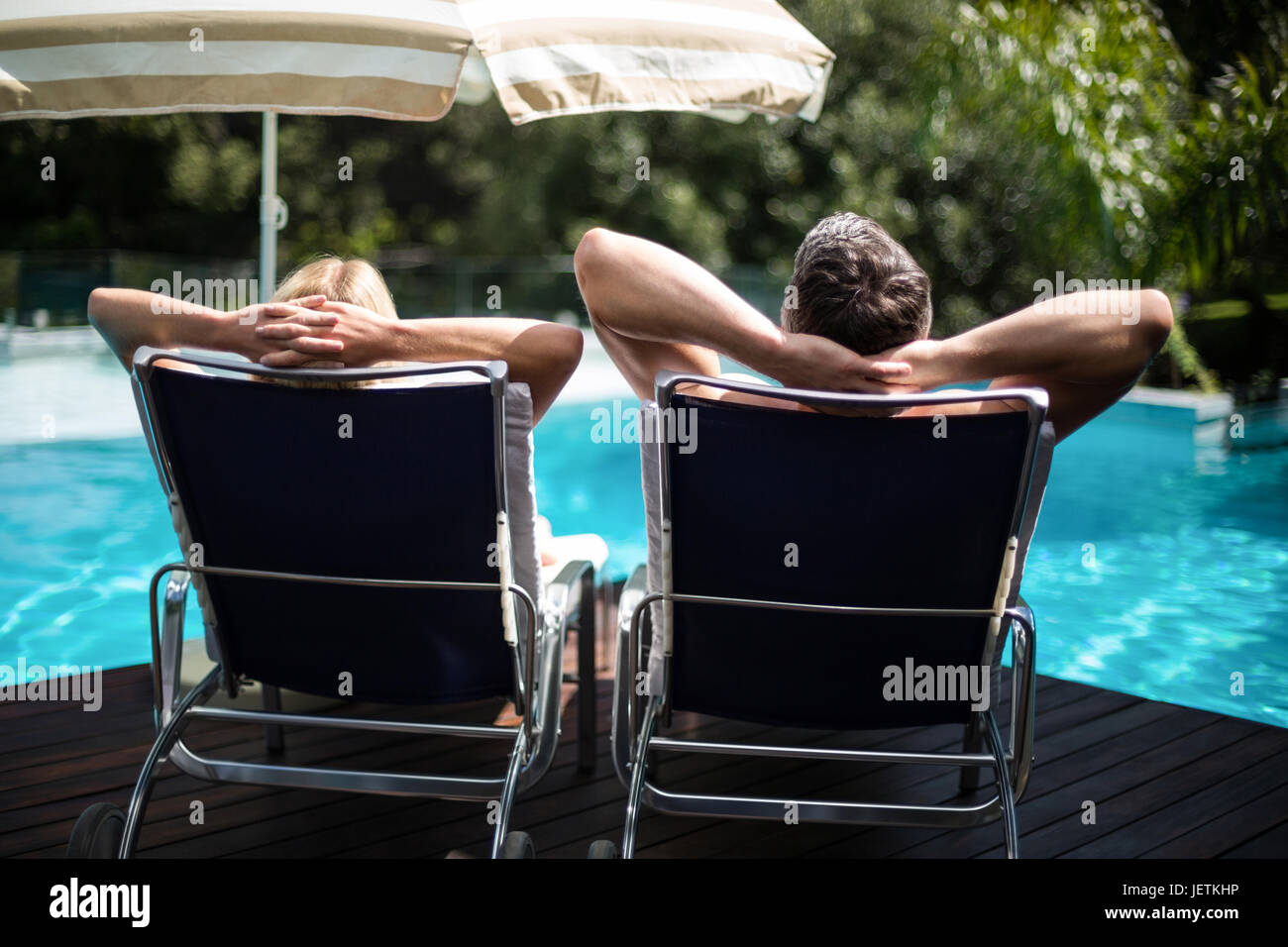 Rear view of couple relaxing on sun lounger Stock Photo - Alamy