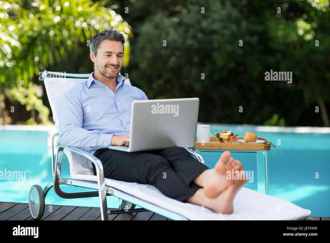 Smart man using laptop near pool Stock Photo - Alamy