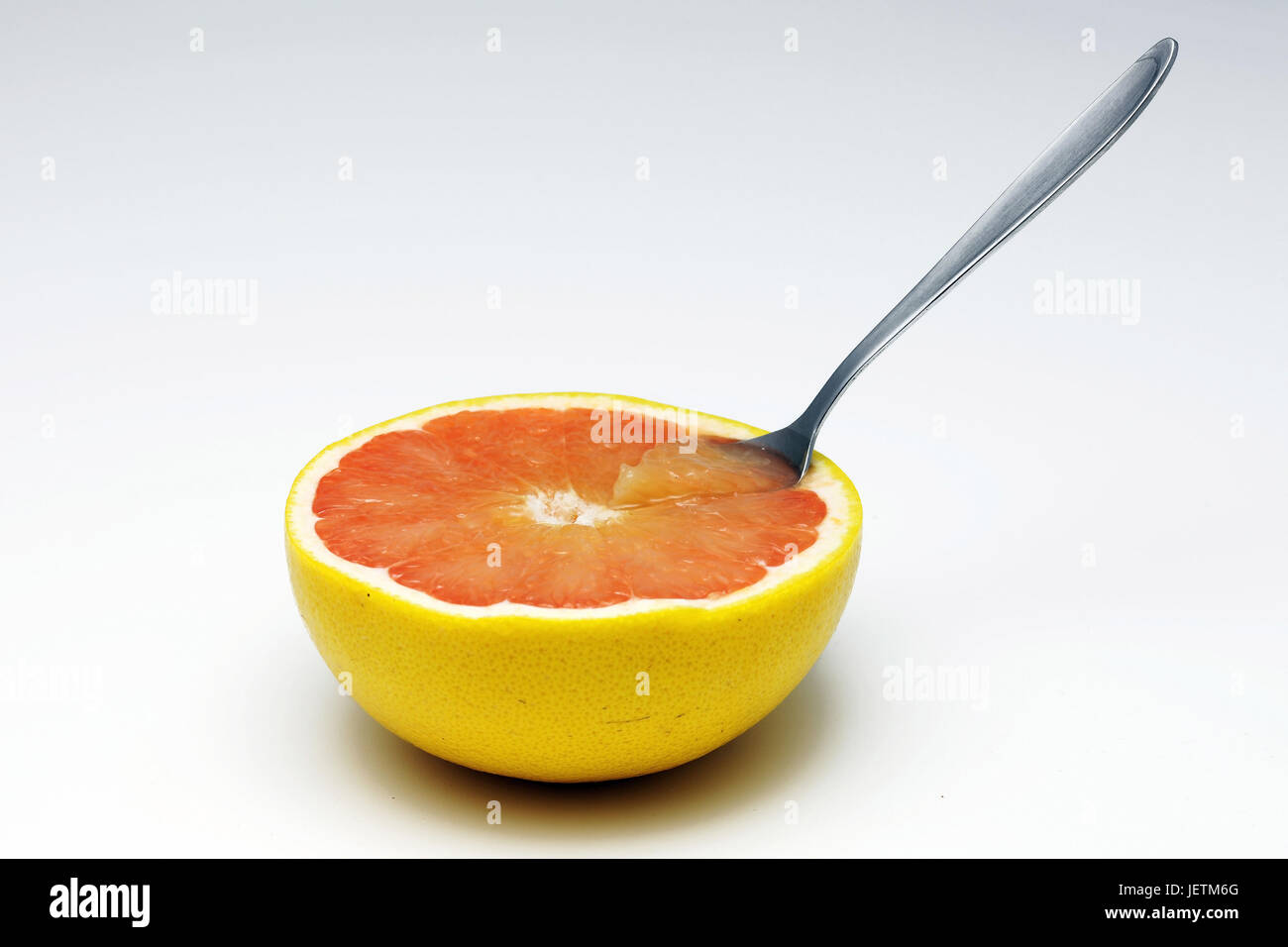 Cut open grapefruit is scraped clean, Aufgeschnittene Grapefruit wird ...