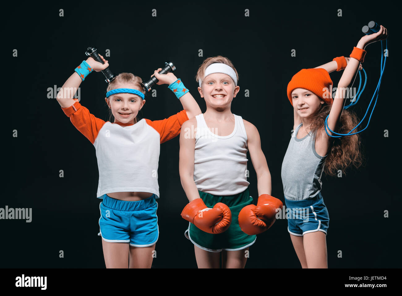 Three smiling kids in sportswear posing with sport equipment and ...
