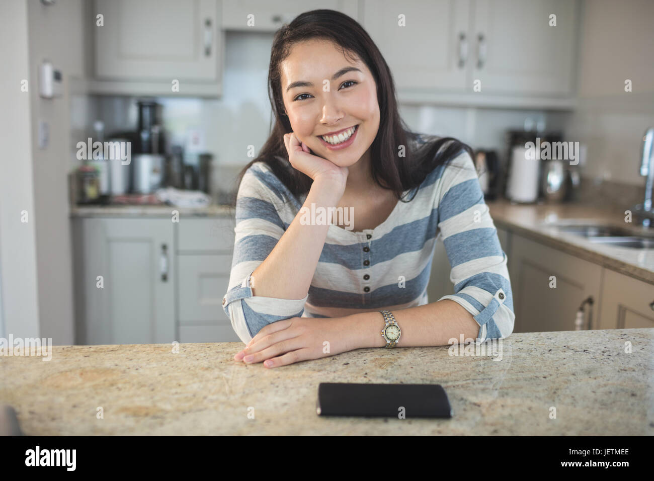 Portrait of happy woman sitting in kitchen Stock Photo - Alamy