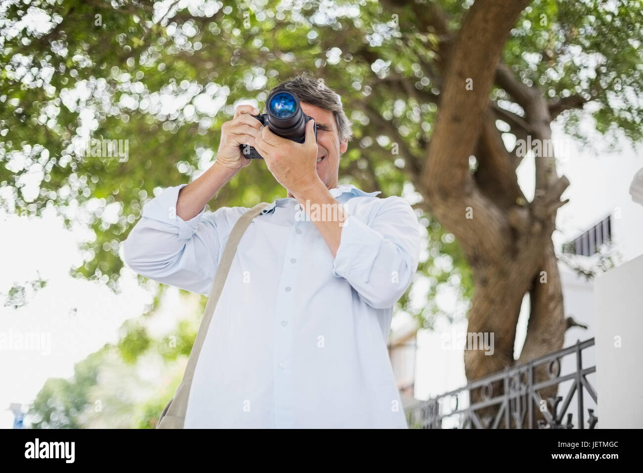 Man using camera against tree Stock Photo - Alamy