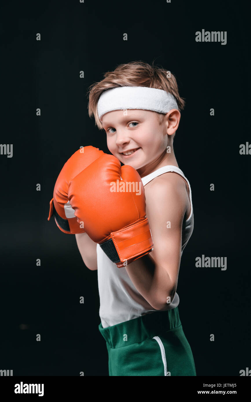 smiling boy in boxing gloves isolated on black, active kids concept ...