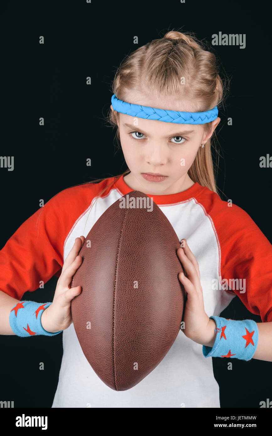 portrait of little sportive girl with rugby ball isolated on black ...