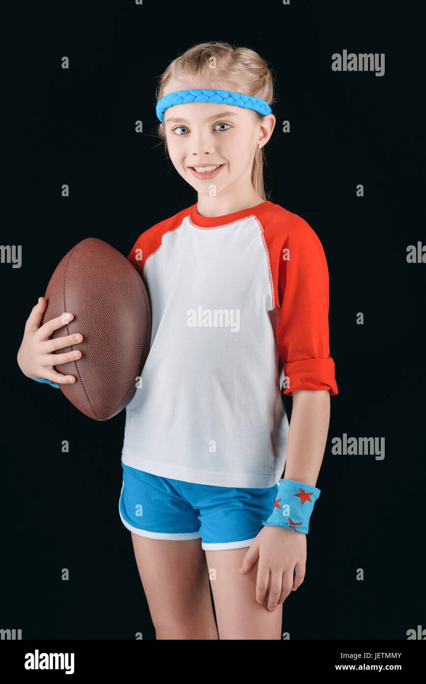 portrait of little sportive girl with rugby ball isolated on black ...