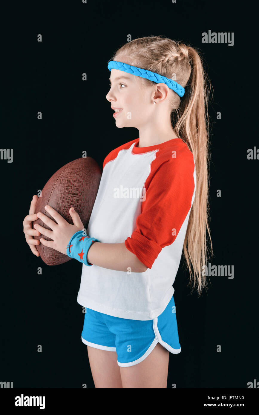 little sportive girl with rugby ball isolated on black, athletics ...