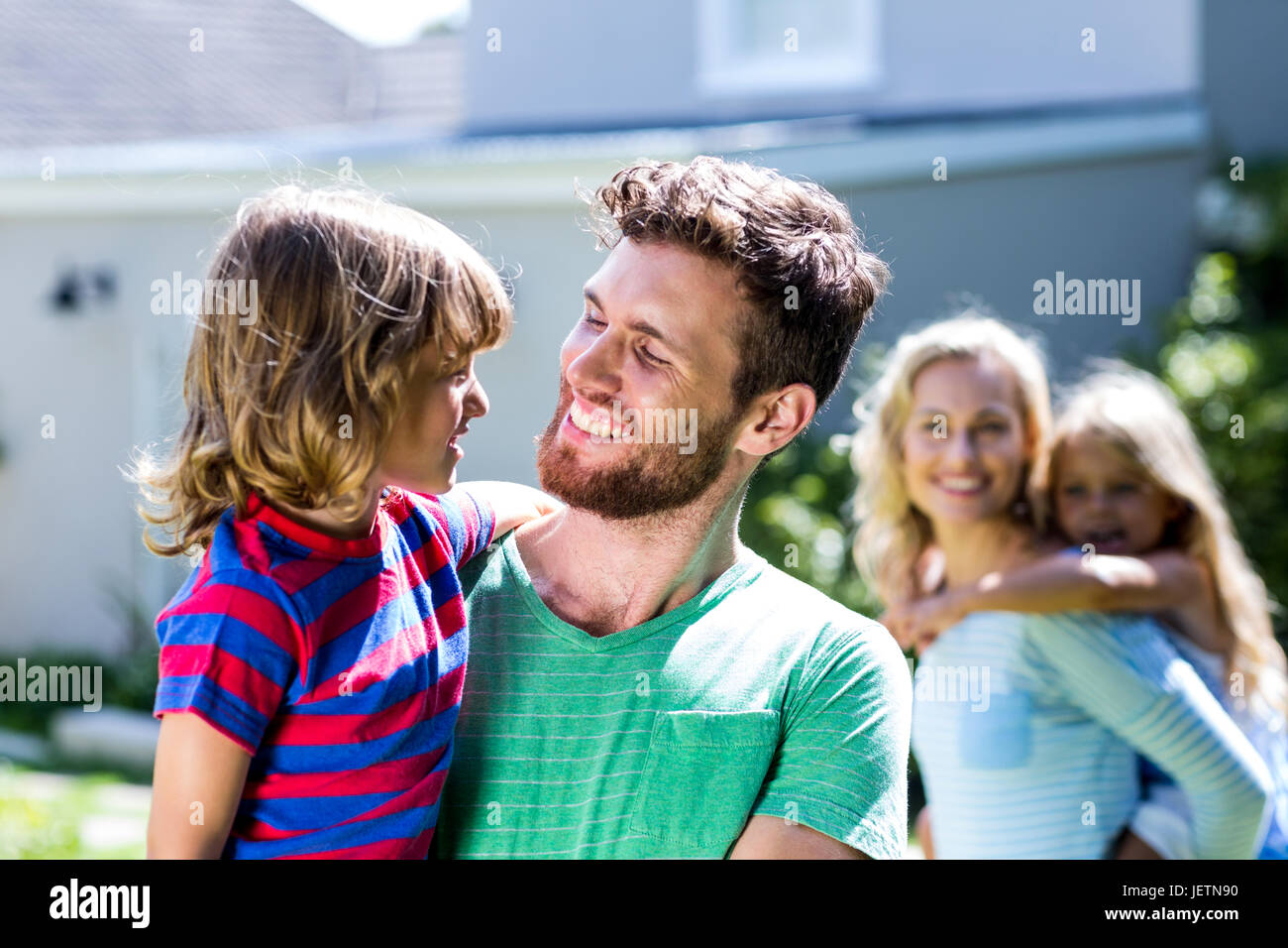 Parent carrying children in yard Stock Photo - Alamy