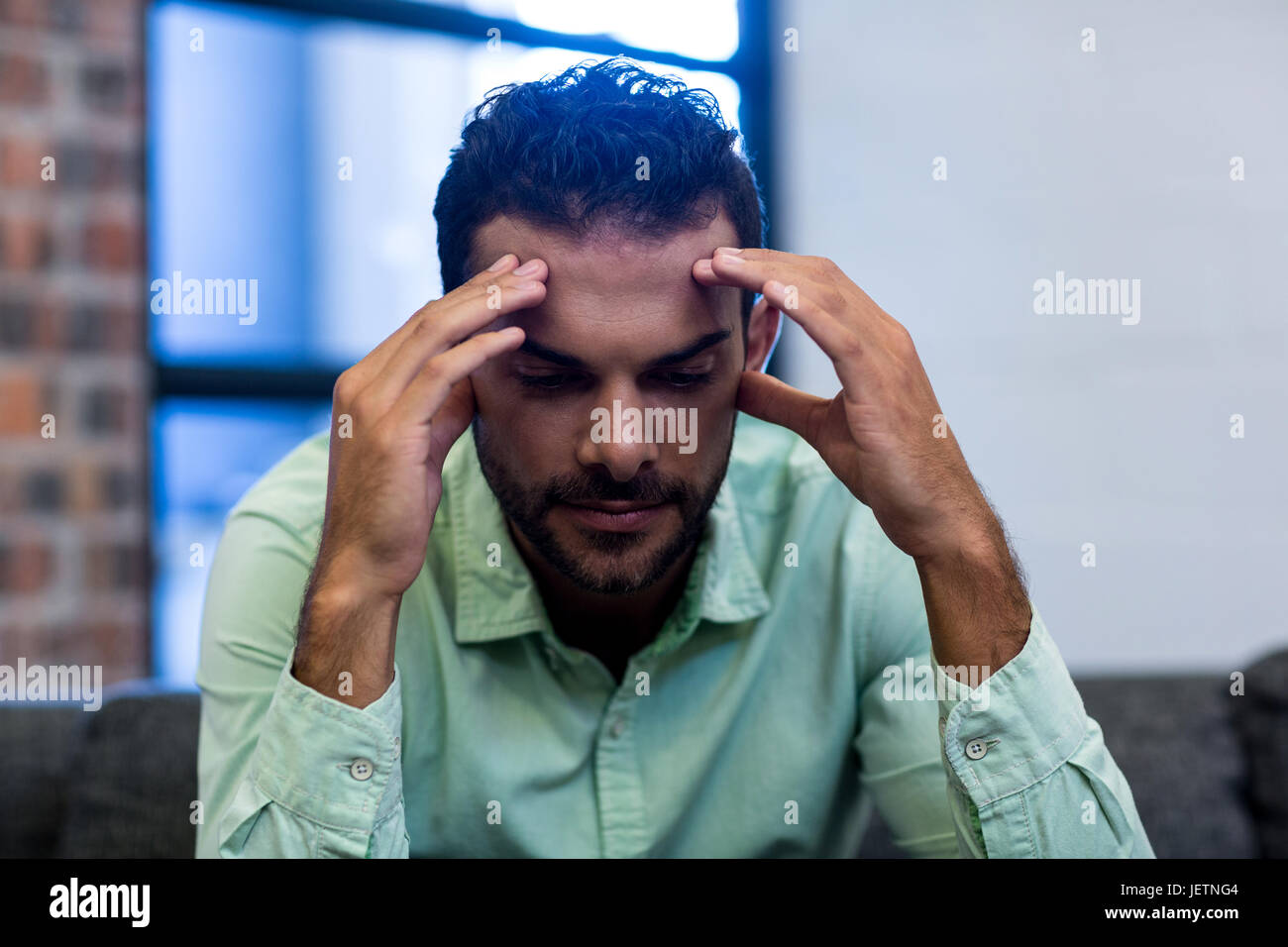 Frustrated young man sitting on sofa Stock Photo - Alamy