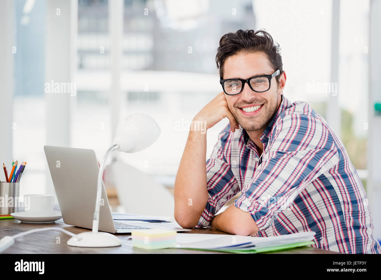 Young man sitting at his desk Stock Photo - Alamy