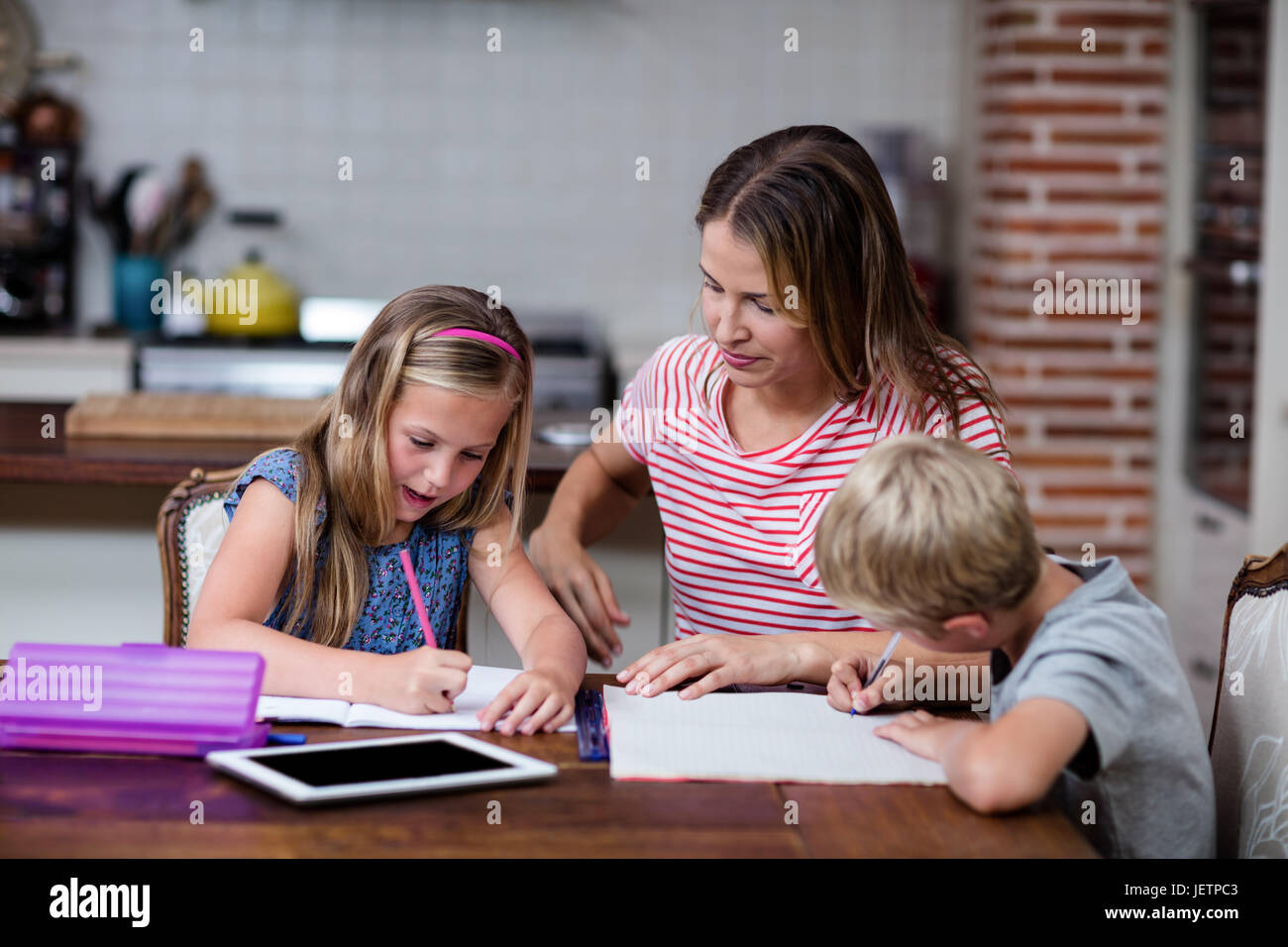 Mother helping kids with their homework Stock Photo - Alamy