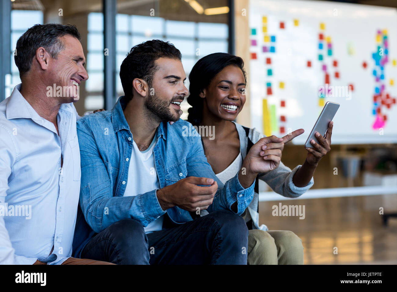 Happy Colleagues using mobile phone Stock Photo - Alamy