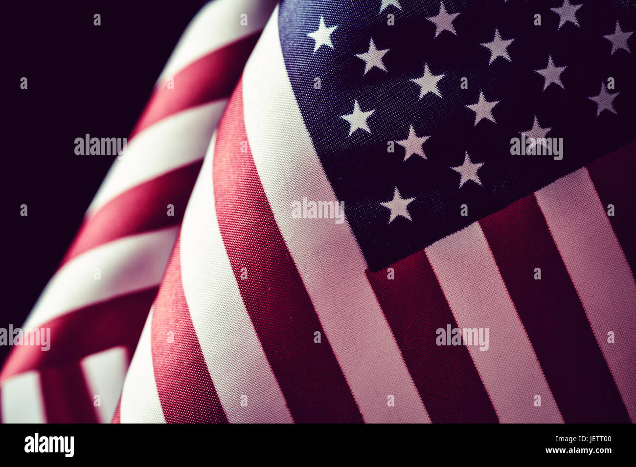 closeup of many american flags put in line, against a black background ...