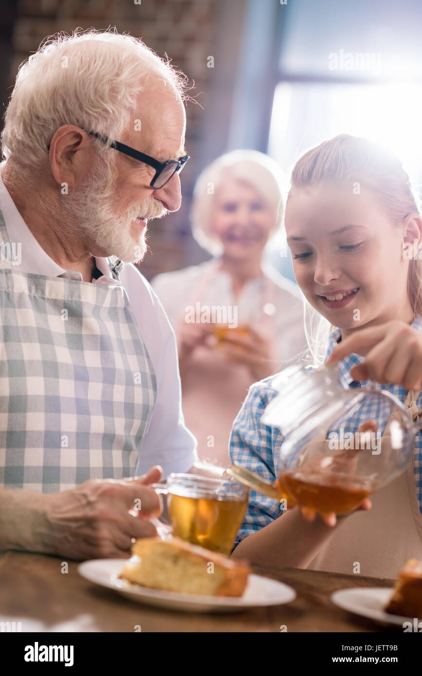 portrait of smiling girl pouring tea in grandfather's cup Stock Photo ...