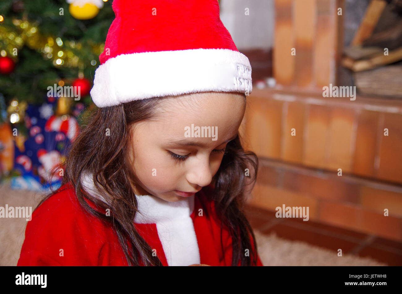 Beautiful sad litle girl wearing a christmas clothes with a christmas ...