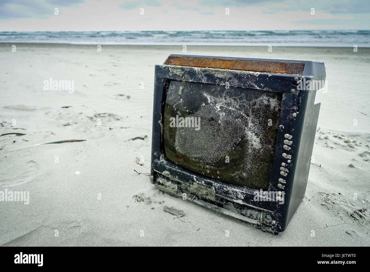 Beach pollution. A rusted and destroyed tv on the beach causing damage ...