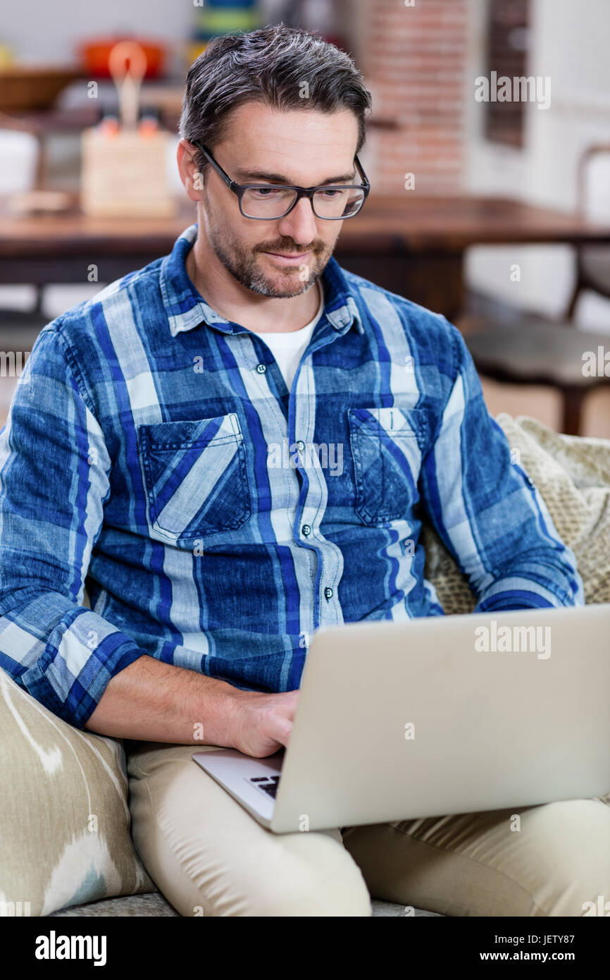 Man sitting on sofa and using a laptop Stock Photo - Alamy