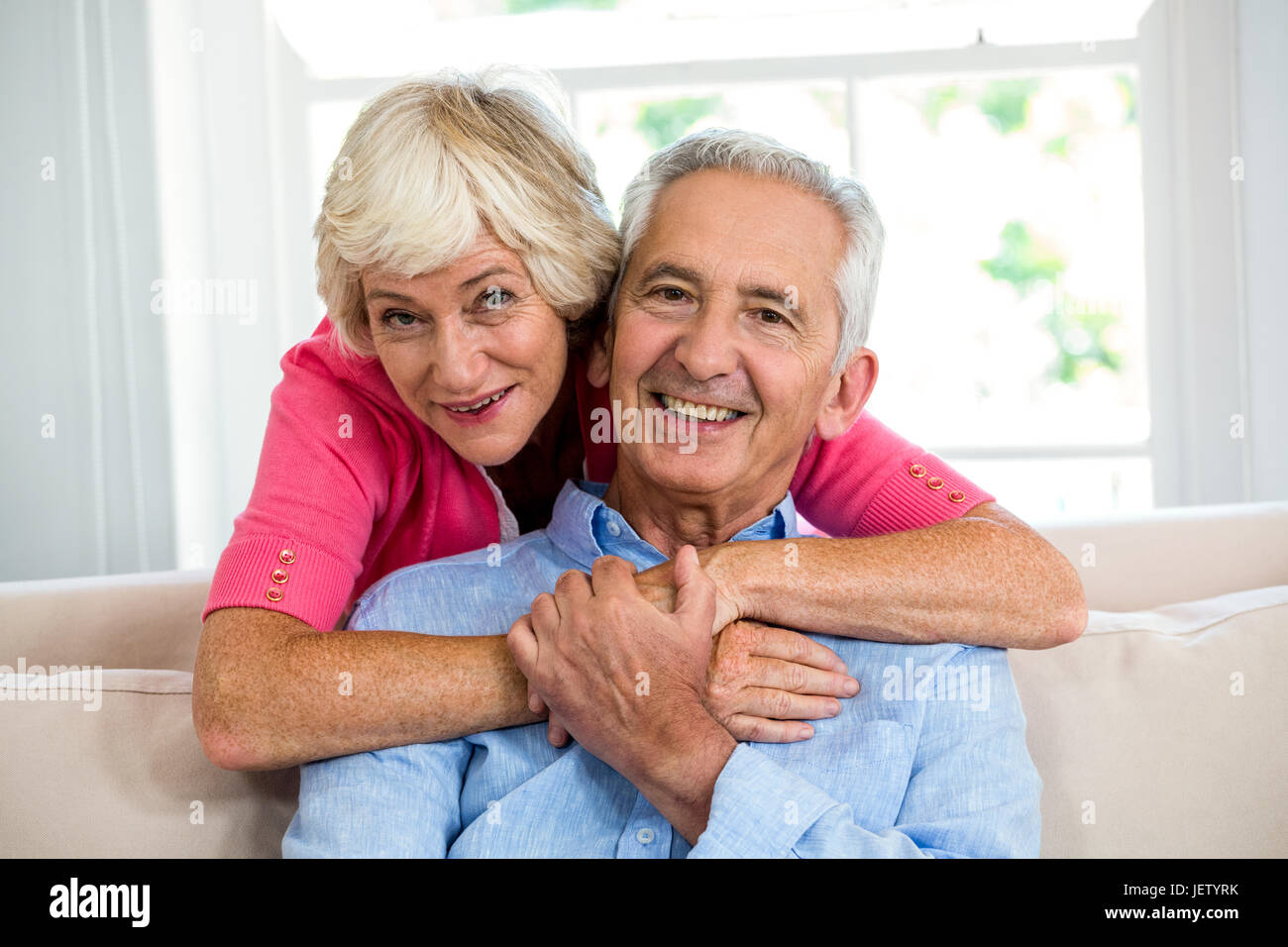 Happy senior couple hugging at sofa Stock Photo - Alamy