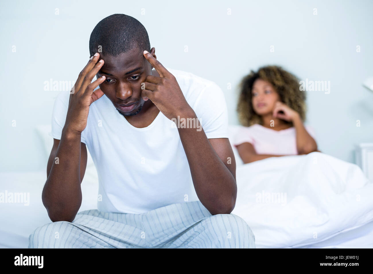 Tensed man sitting on bed in bedroom Stock Photo - Alamy