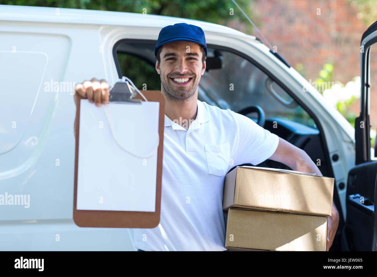 Smiling delivery man showing clipboard Stock Photo - Alamy