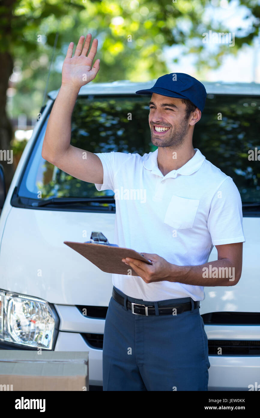 Smiling delivery man waving hand Stock Photo - Alamy