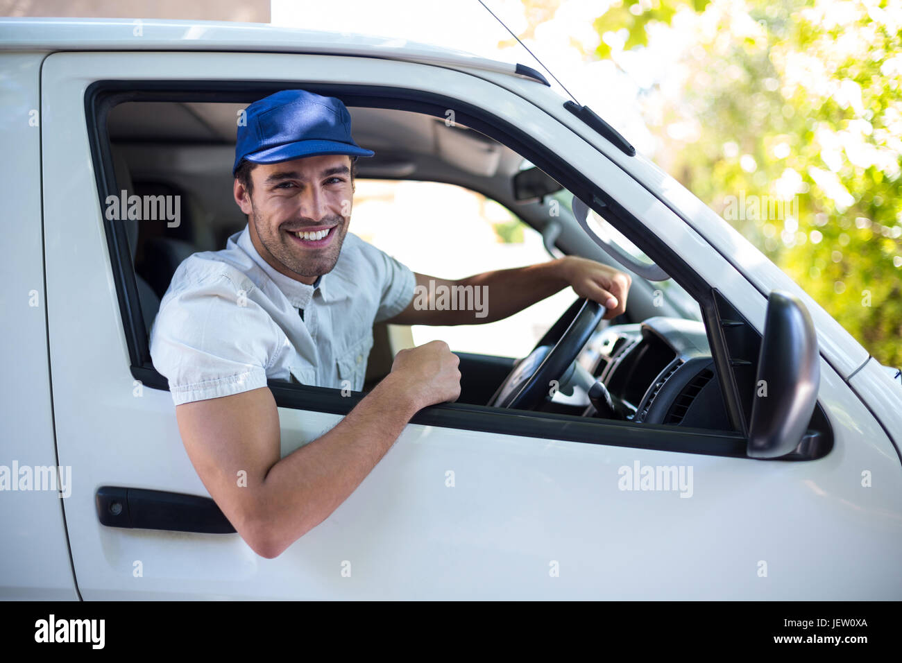Smiling delivery man sitting in van Stock Photo - Alamy