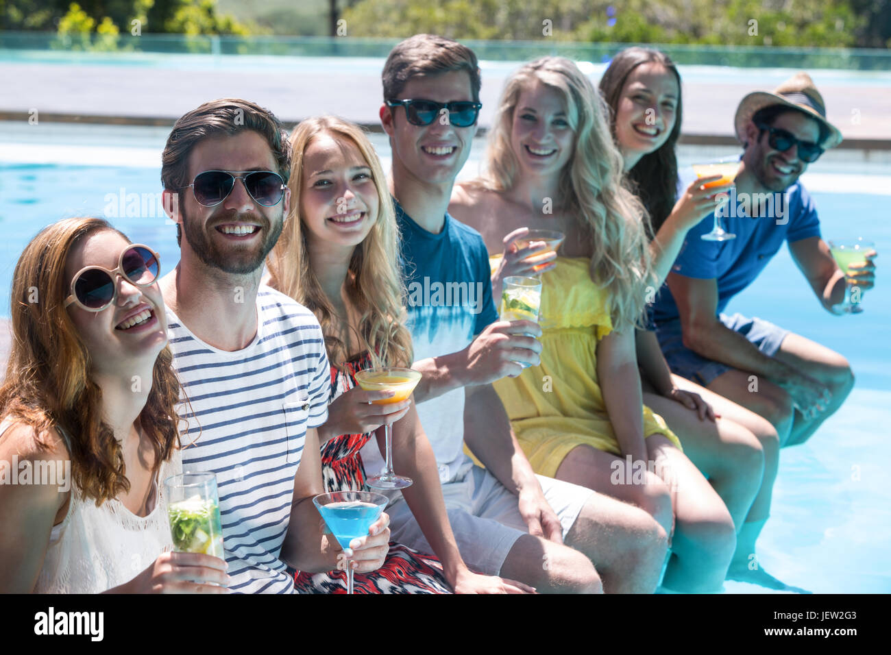 Happy friends sitting in swimming pool Stock Photo - Alamy