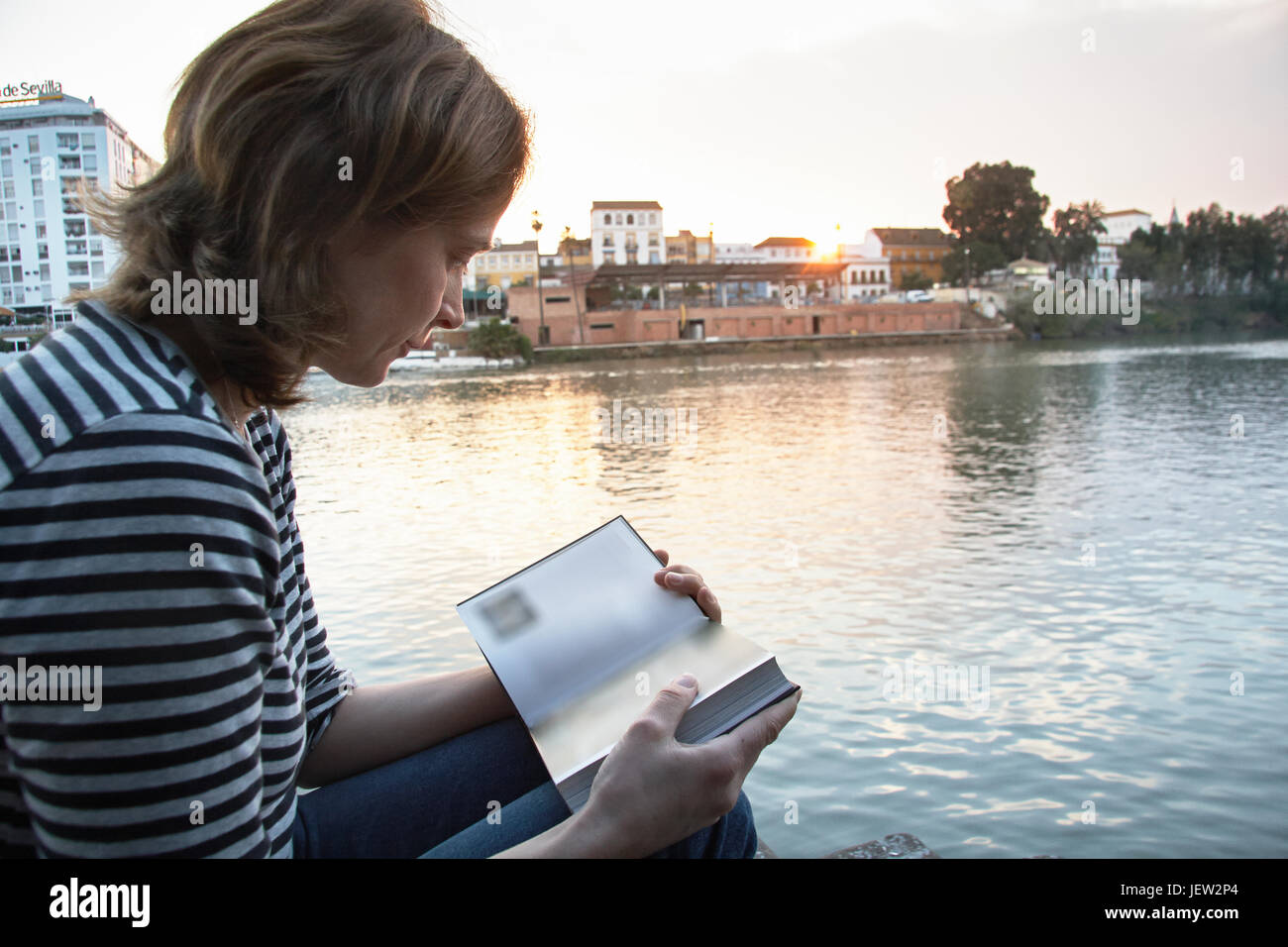 Woman reading book at water Stock Photo - Alamy